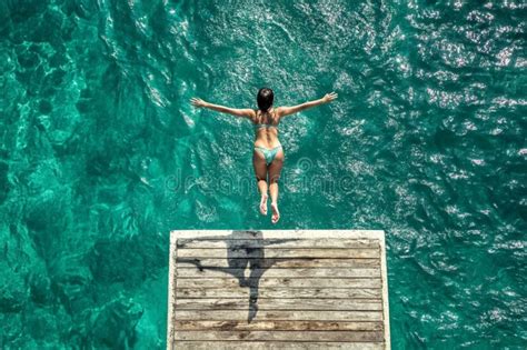 Young Woman Jumping Into Emerald Water From Stone Steps Stock Image
