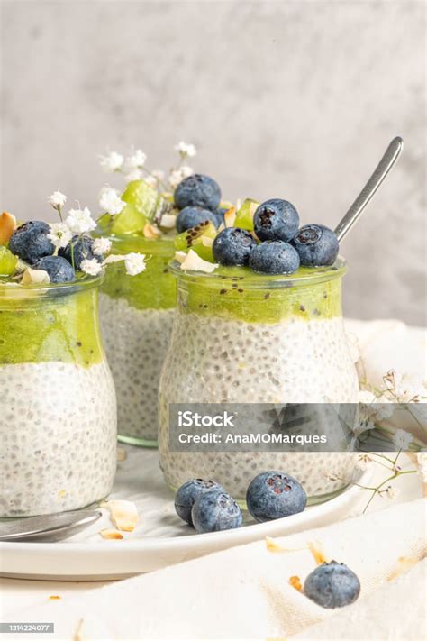 키위 블루베리 코코넛 슬라이스가 있는 건강한 아침 식사 치아 푸딩 흰색 테이블에 유리 항아리에 3 개 0명에 대한 스톡 사진 및