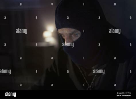 Male Hacker In The Hood In A Dark Room Using Computer Virus Program For Cyber Attack Hackers