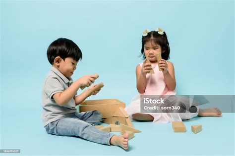 스튜디오의 파스텔 블루 배경에 나무 장난감 블록과 함께 놀고 아시아 두 사람 아이들 어린이의 기술 어린 시절 역할과 출생 순서 아동 개발 개념 2 3 살에 대한 스톡 사진
