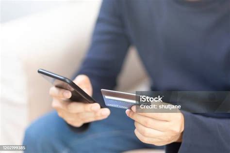 남자는 스마트 폰과 신용 카드와 파란색 티셔츠 손을 착용합니다 교환에 대한 스톡 사진 및 기타 이미지 교환 구매 금융