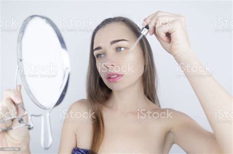 얼굴 용 세럼 흰색 배경의 소녀는 피펫으로 얼굴에 레티놀을 바릅니다 레티노이드 히알루 론산 산 필링 문제가있는 복합성 피부 주름과 건조의 치료 주름에 대한 스톡 사진 및