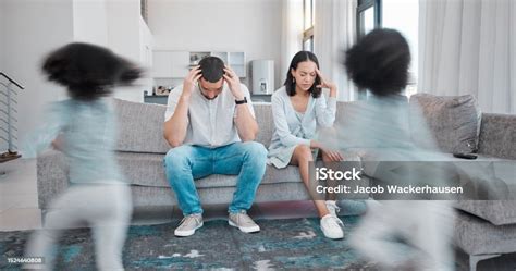 어머니 아버지 그리고 집에서 소파에 앉아 부모를 괴롭히는 거실에서 바쁘게 뛰어다니는 아이와 함께 번아웃에 스트레스를 받습니다