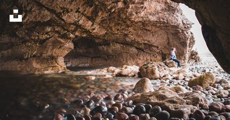파란 셔츠와 파란 데님 청바지를 입은 남자가 낮에 바위 해안에 서 있다 사진 Unsplash의 무료 바다 이미지