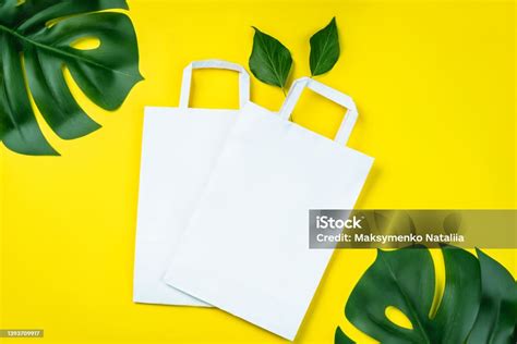 노란색 배경에 환경 친화적 인 종이 봉지 노란색 배경에 녹색 잎이있는 재활용 종이 쇼핑백 폐기물 제로 플라스틱 없는 개념 환경