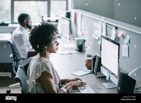 Side View Of Business People Using Desktop Computers While Working In