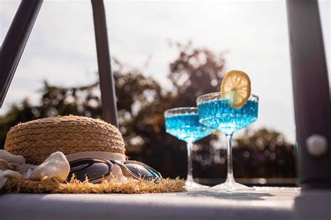 수영장 배경에 맛있는 파란색 칵테일 블루 라군과 노란색 레몬 한 잔 알콜 칵테일 육즙이 많은 과일 블루와 Curacao 리큐어 아이스 큐브 및 레몬 조각 0명에 대한 스톡