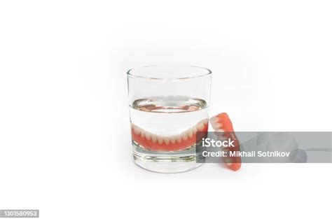 물 한 잔의 틀니 치과 보철 관리 턱의 전체 이동식 플라스틱 틀니 두 개의 아크릴 의치 가짜 이빨이있는 위쪽과 아래턱 틀니 또는 거짓 치아 복사 공간 0명에 대한 스톡 사진