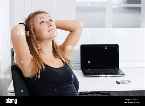 Portrait Of Young Businesswoman With Hands Behind Head Sitting In Front