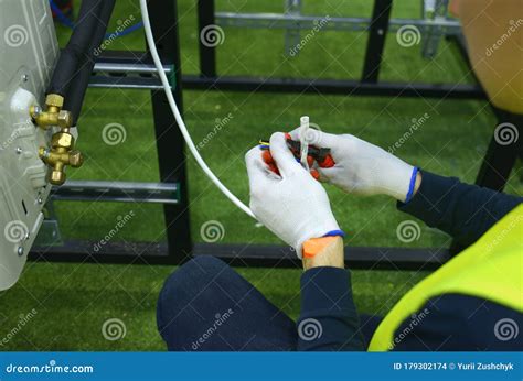 Male Fitter Hands In Gloves Assembling Air Conditioner With Pliers