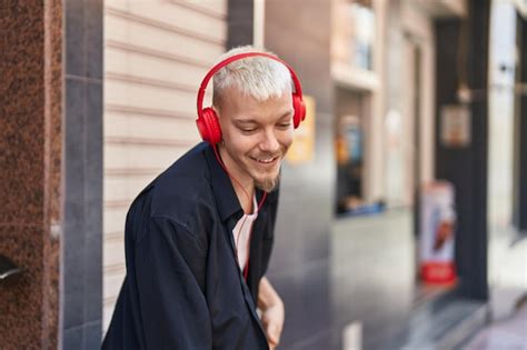 Jovem homem caucasiano sorrindo confiante ouvindo música e dançando na