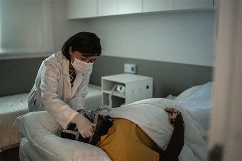 의사가 환자의 머리에 전극을 배치하여 건강 검진을 받으며 보호용 얼굴 마스크를 착용합니다 수면중무호흡증에 대한 스톡 사진 및