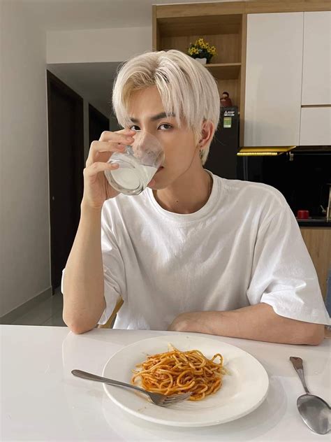 A Man Drinking Water While Sitting At A Table With Food And Utensils In Front Of Him
