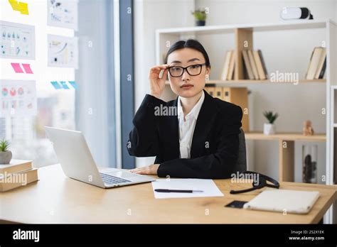 Asian Businesswoman In Formal Attire Working On Laptop In Modern Office