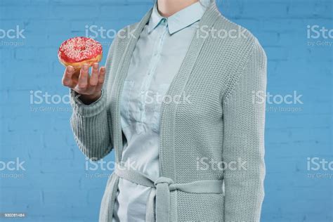 자른 스웨터와 셔츠 블루 벽돌 벽 앞 맛 있는 유약된 도넛을 들고 있는 여자의 샷 건강에 좋지 않은 음식에 대한 스톡 사진 및 기타 이미지 건강에 좋지 않은 음식