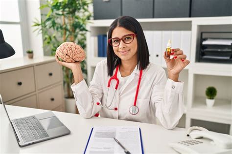 Young Hispanic Doctor Woman Holding Brain And Cbd Oil Smiling With A