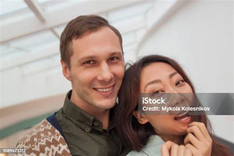 쇼핑몰에서 젊은 국제 커플 복용 Selfie입니다 소송 함께 확인 Selfie 사진에 그녀의 잘생긴 남자 친구와 함께 행복 한