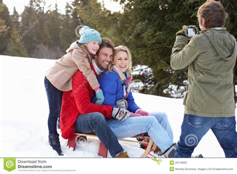 Familia Joven Que Se Sienta En Un Trineo En La Nieve Foto De Archivo