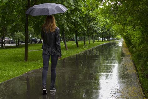 Женщина идя с черным зонтиком под дождем в парке Стоковое Изображение изображение