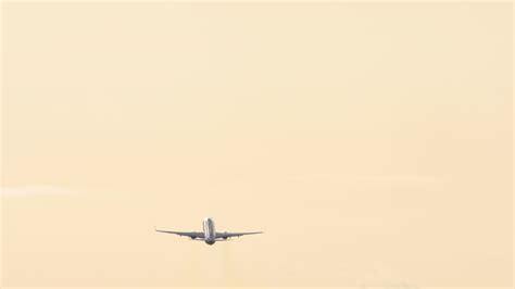 Cinematic Shot Of A Jet Plane Flying Away At Sunrise Or Sunset Sun