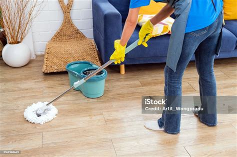 두 명의 젊은 아시아 전문 청소 서비스 여성 노동자 팀이 집에서 일하고 있습니다 소녀 가정부는 젖은 걸레로 나무 바닥을 닦고 다른 걸레로 깃털 먼지떨이로 창문을 닦았습니다