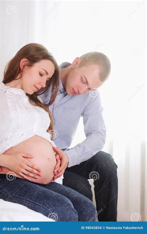Husband Touching Pregnant Tummy Of His Charming Joyful Wife Which Lying