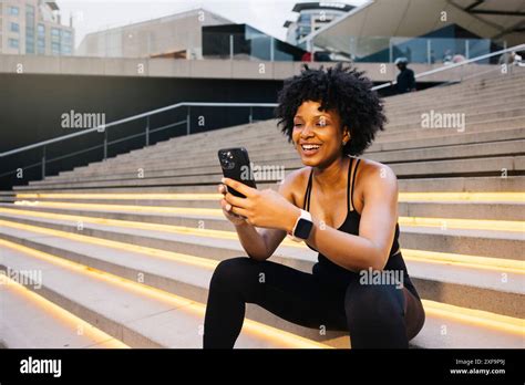 Young Cheerful Woman Sitting On Illuminated Steps Taking A Selfie After
