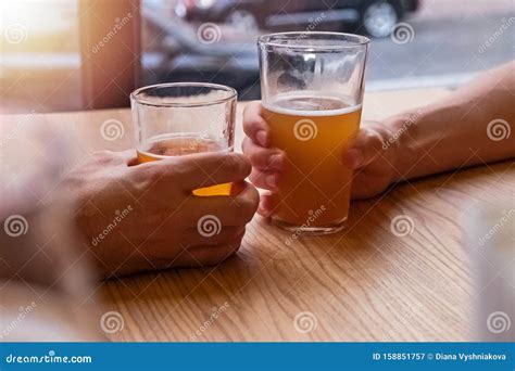 Two Man`s Hands Holding Beer Glasses Or Clinking In The Pub Stock Image