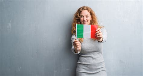 서 치아를 보여주는 자신감 미소로 웃 고 행복 한 얼굴로 이탈리아의 국기를 들고 회색 그런 지 벽에 빨강 머리 젊은 여자 기에 대한 스톡 사진 및 기타 이미지 Istock