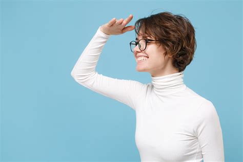 파스텔 블루 배경에서 고립된 포즈를 취하는 캐주얼한 흰색 옷 안경을 쓰고 미소짓는 젊은 여성 소녀 사람들 라이프 스타일 개념