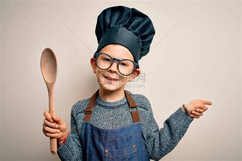 身着厨服和帽子用木勺子做饭的幼小caucasians儿童非常快乐地用手和高清图片下载 正版图片504086050 摄图网