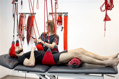 남성 환자에게 서스펜션 스트랩에 적극적인 치료를 하고 있는 재활 전문가 2명에 대한 스톡 사진 및 기타 이미지 2명 건강