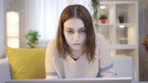 focado e sério jovem mulher às casa olhando às computador portátil