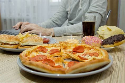 남자는 컴퓨터에서 작동 하 고 패스트 푸드를 먹는다 건강에 해로운 음식 햄버거 소스 감자 도넛 칩 감자 요리에 대한 스톡 사진 및 기타 이미지 Istock