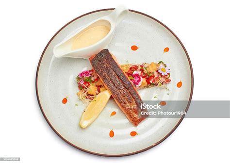 토마토 살사와 라임이 아름다운 꽃으로 장식된 구운 연어의 탑 뷰 흰색 배경에 분리된 큰 도자기 접시에 크림 샐러드와 얇게 썬