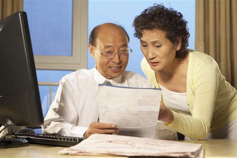 老年人两个人丈夫妻子坐横图室内正面仰视商务通讯合作窗帘报纸北京中国亚洲眼镜t恤活力投资摄影退休