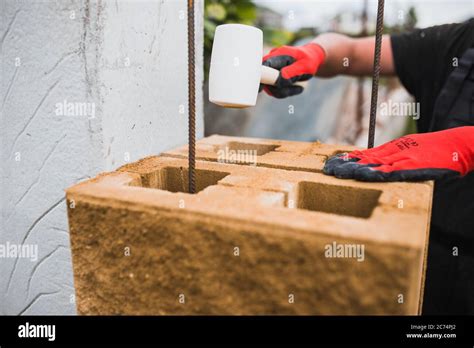 A Professional Bricklayer Builds Pillars For A Stone Fence From Cement Blocks Support Fence Of