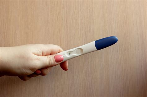 여자는 가벼운 배경에 부정적인 임신 테스트를 들고 분홍색 손톱과 손입니다 모성 임신 피임의 개념 건강 문제 및 임신 문제 복사
