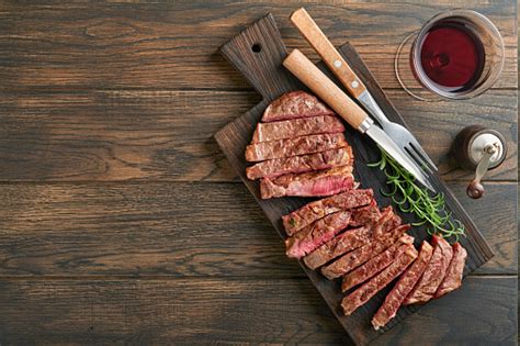 스테이크 얇게 썬 구운 고기 스테이크 뉴욕 또는 Ribeye는 오래된 나무 배경에 검은 대리석 보드에 향신료 로즈마리와 후추를