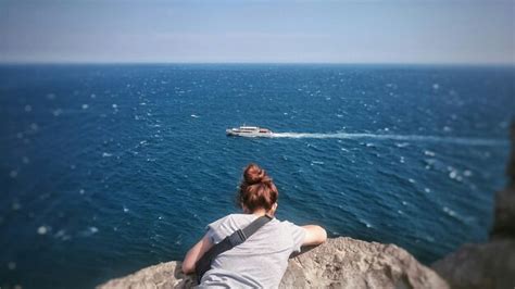 Premium Photo Rear View Of Woman Lying On Rock At Seaside