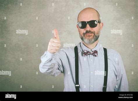 Happy Man With Sunglasses And Bow Tie Showing Thumbs Up Against Gray