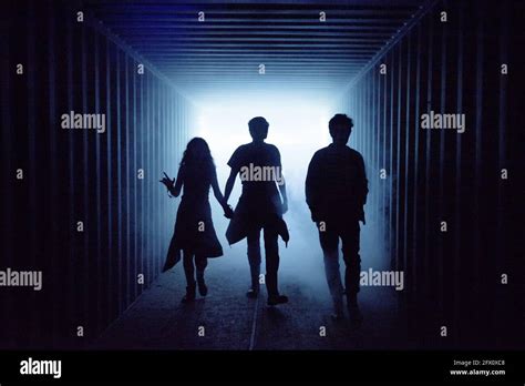 Silhouette Of People Walking In A Dark Subway Tunnel To The Light Stock