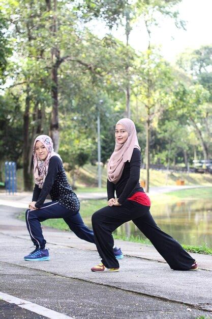 Premium Photo Sisters Wearing Hijab While Exercising By Lake At Park