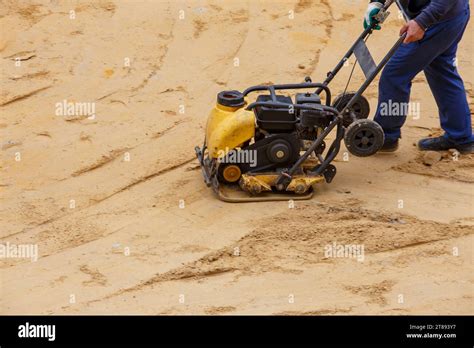 Worker Using Vibratory Plate Compactor For Compaction Sand During Path