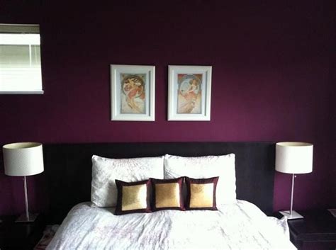 A White Bed With Two Framed Pictures On The Wall Above It And Lamps