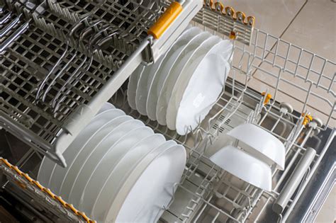 깨끗한 요리가있는 개방형 식기 세척기의 상단 전망 흰색 접시 머그잔 숟가락 및 포크가있는 선반을 꺼내십시오 내장 된 가전 제품이있는 베이지 색 주방 0명에 대한 스톡 사진