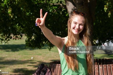 쾌활 한 여 자가 총을 촬영 제스처를 만드는 아름 다운 젊은 여성이 도시 공원에서 여가 시간을 즐기고 돌고 웃 고 카메라에서 몸짓을 하 고 있습니다 몸짓 개념 개념에 대한