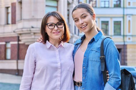 Portrait Of Happy Mom And Teenage Daughter Looking At Camera Outdoor On