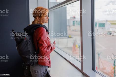 공항 게이트에서 여권을 손에 들고 창문을 들여다 보는 여성 승객 45 49세에 대한 스톡 사진 및 기타 이미지 45 49세 가방 게이트 Istock