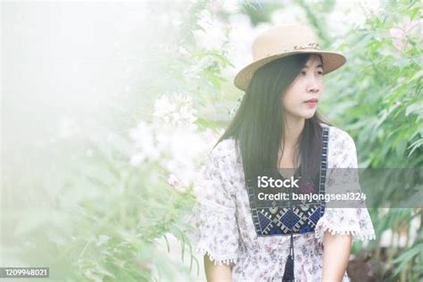 화려한 목도리와 밀짚 모자와 검은 조끼에 아름다운 여자 보라색 Verbena 보나리엔시스 꽃 밭에서 포즈 검은 긴 머리와 매력적인 중국 여자 는 야외에서 그녀의 여가 시간을